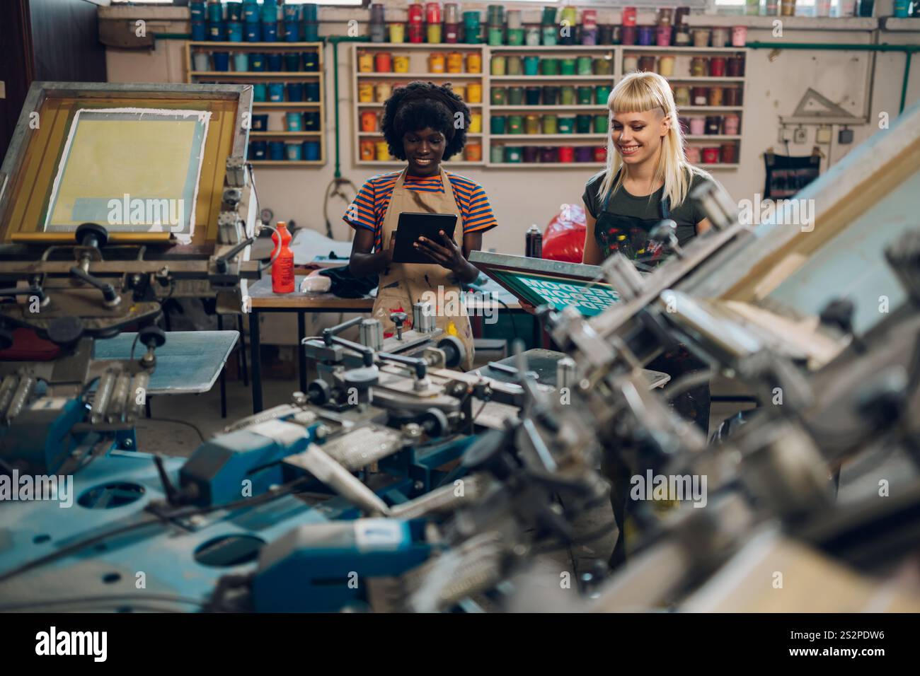 Multicultural smiling female printing shop workers preparing printing ...
