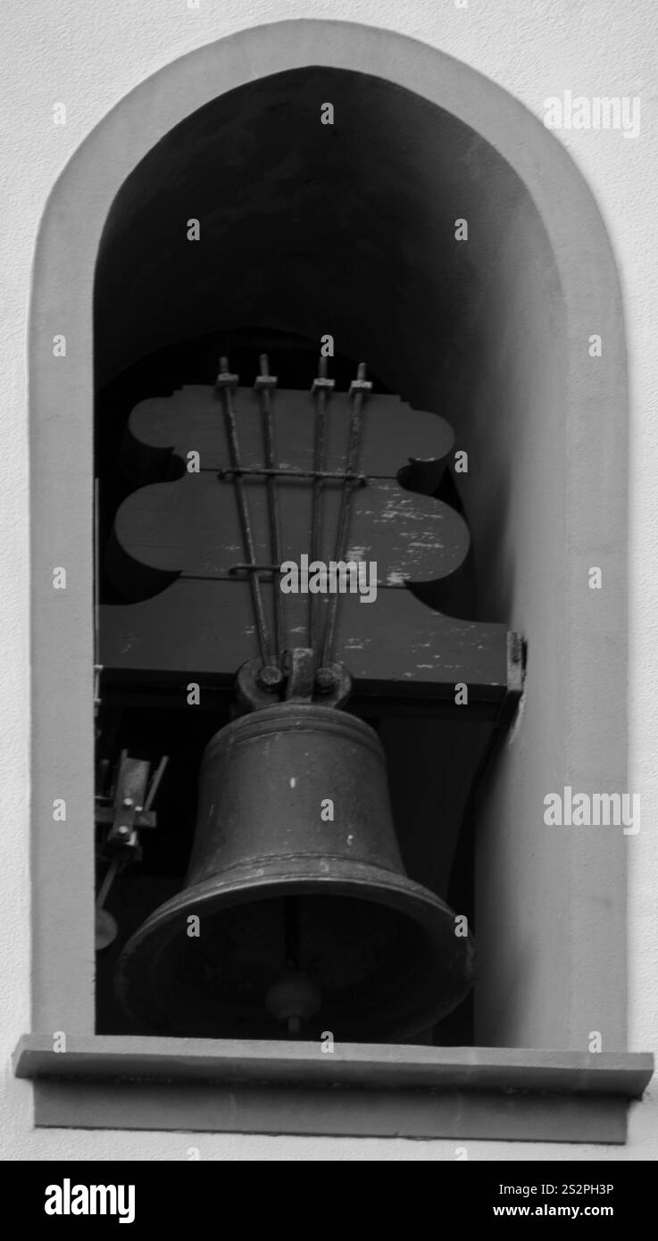 A black-and-white photo of a large bell housed in an arched alcove of a ...