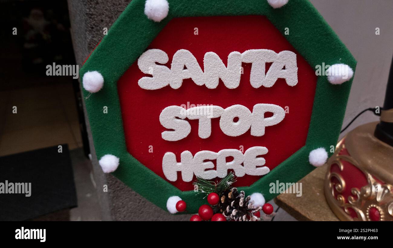 A festive “Santa Stop Here” sign in bright red, green, and white with ...