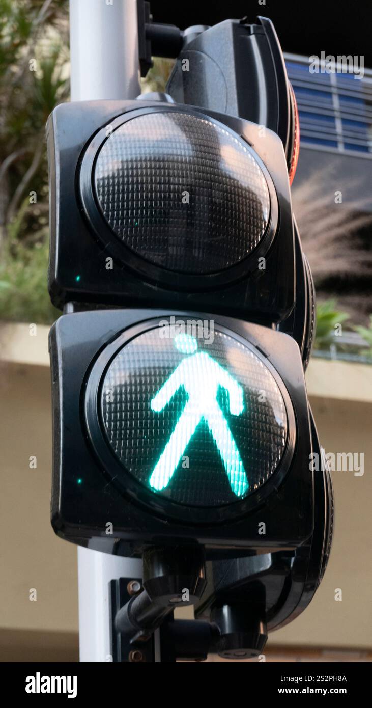 A close-up of a pedestrian traffic light displaying a green walking ...