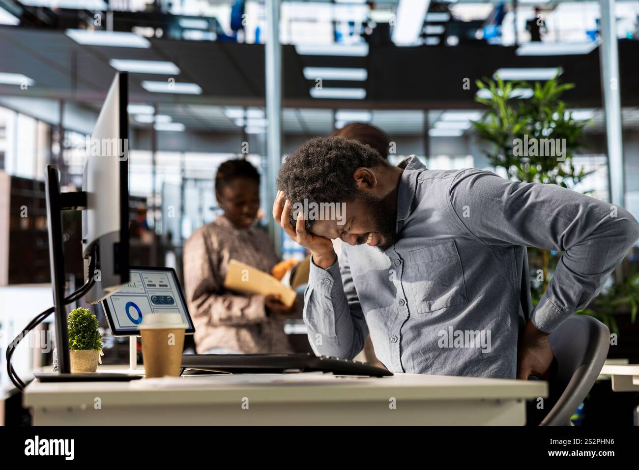 Black enterprise worker takes a break and stretches his back muscles ...
