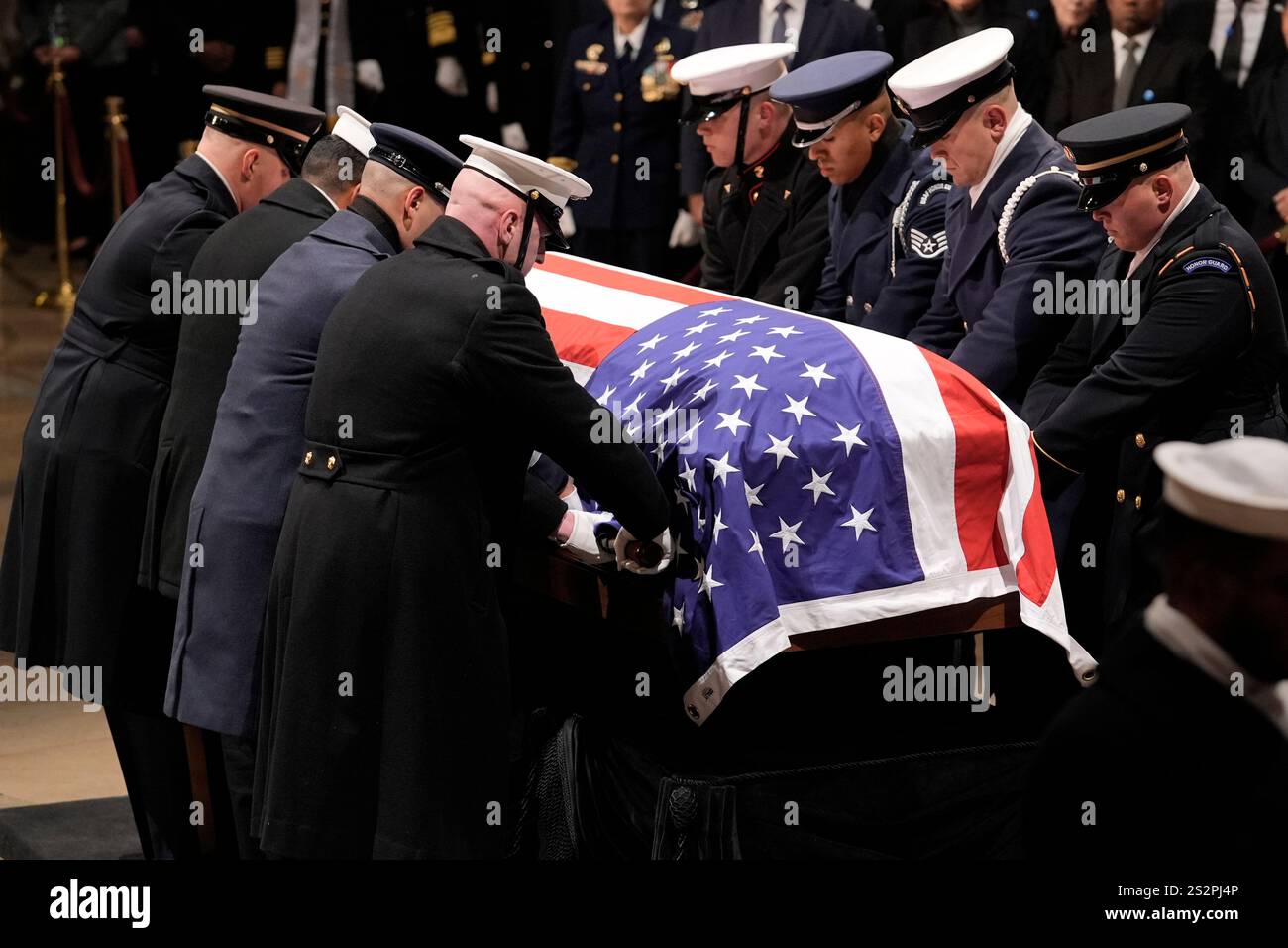A joint services military honor guard places the flag-draped casket of ...