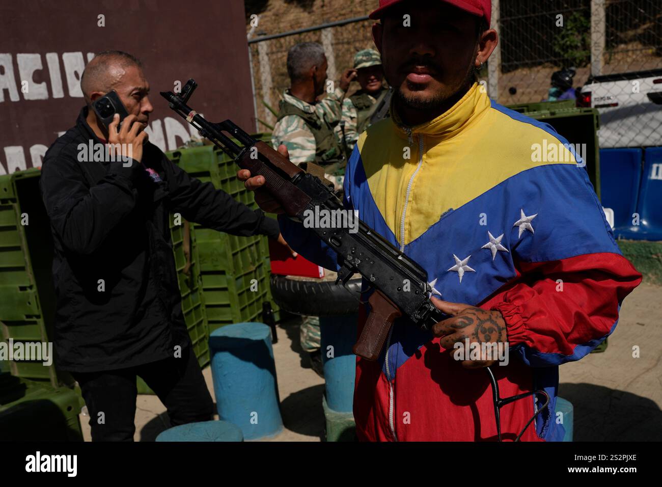 A man wearing a jacket designed like the Venezuelan flag holds a weapon ...