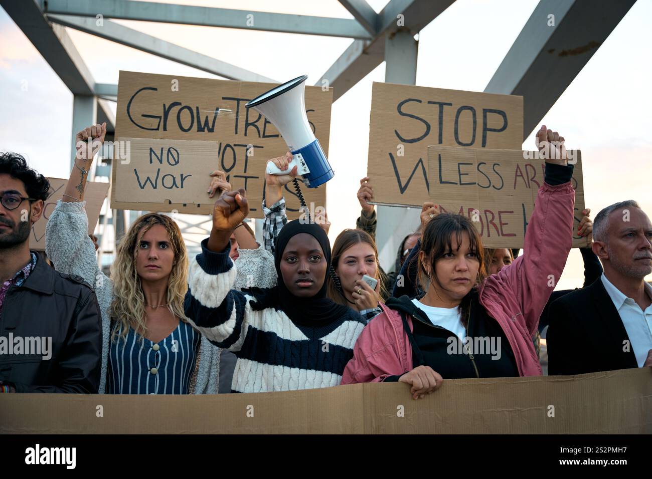 Serious multiracial adult group with fist raised demonstrating against ...