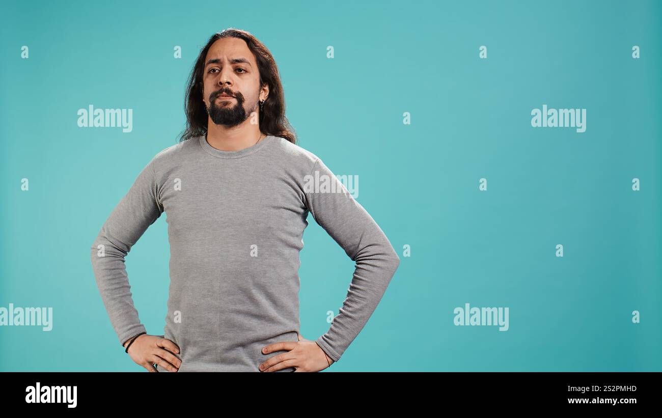 Portrait of man standing confidently with hands on hips, posing against ...