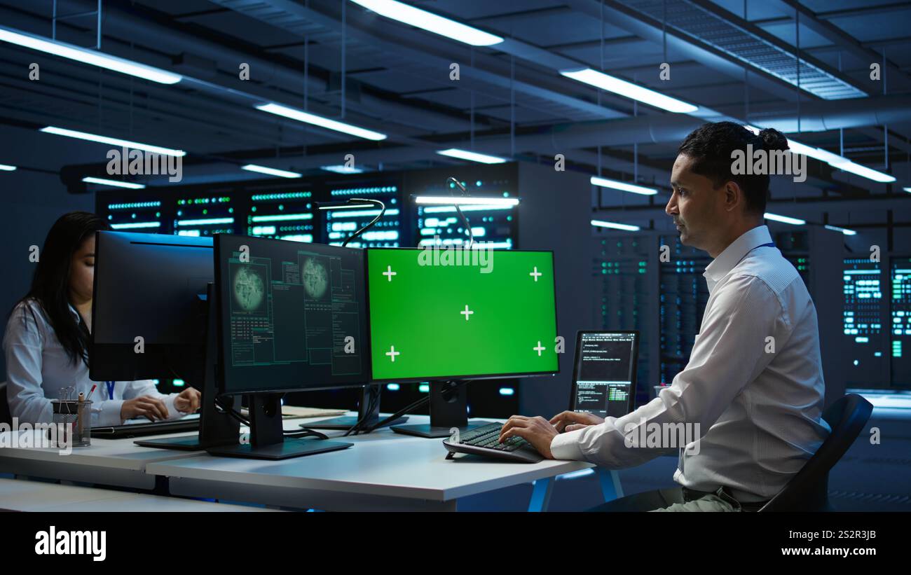 Engineer in server hub using green screen PC to stop hacker passing company firewall and ...