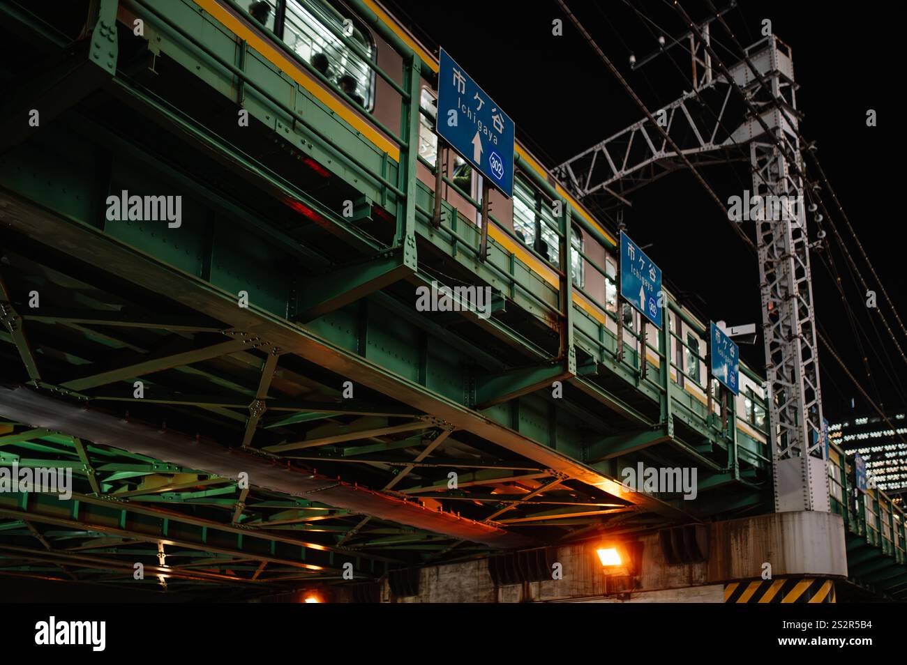 Urban night scene featuring a train passing over a green steel railway ...
