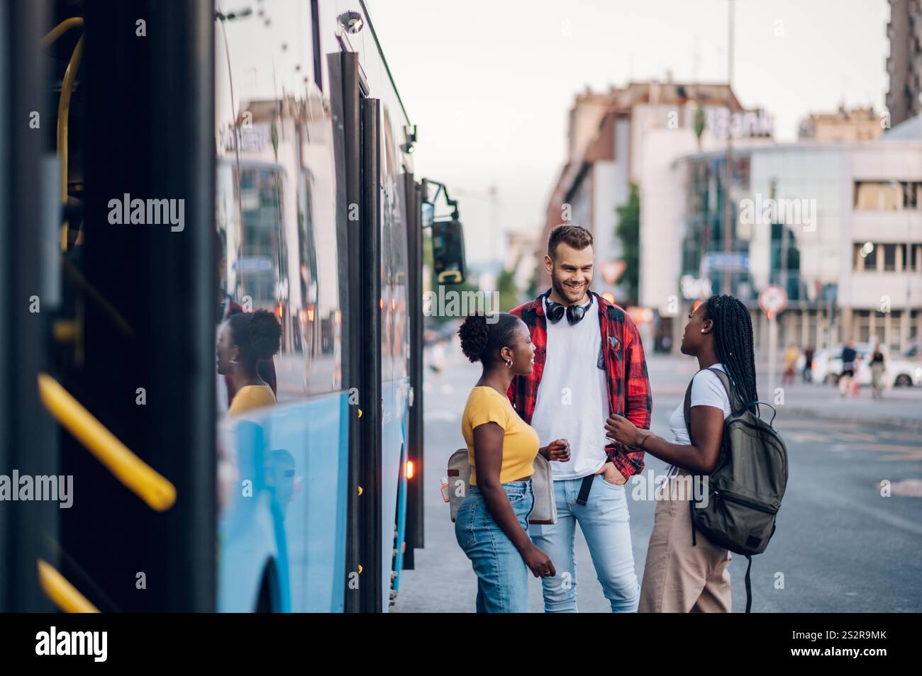 Diverse group of friends waiting for a bus while at a bus stop. Riding ...
