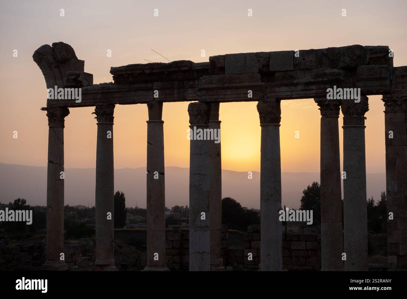 The beautiful sun is slowly setting behind the impressive columns of an ...