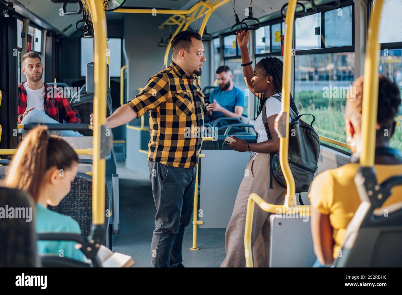 Young diverse couple of friends chatting on a bus together. Two ...