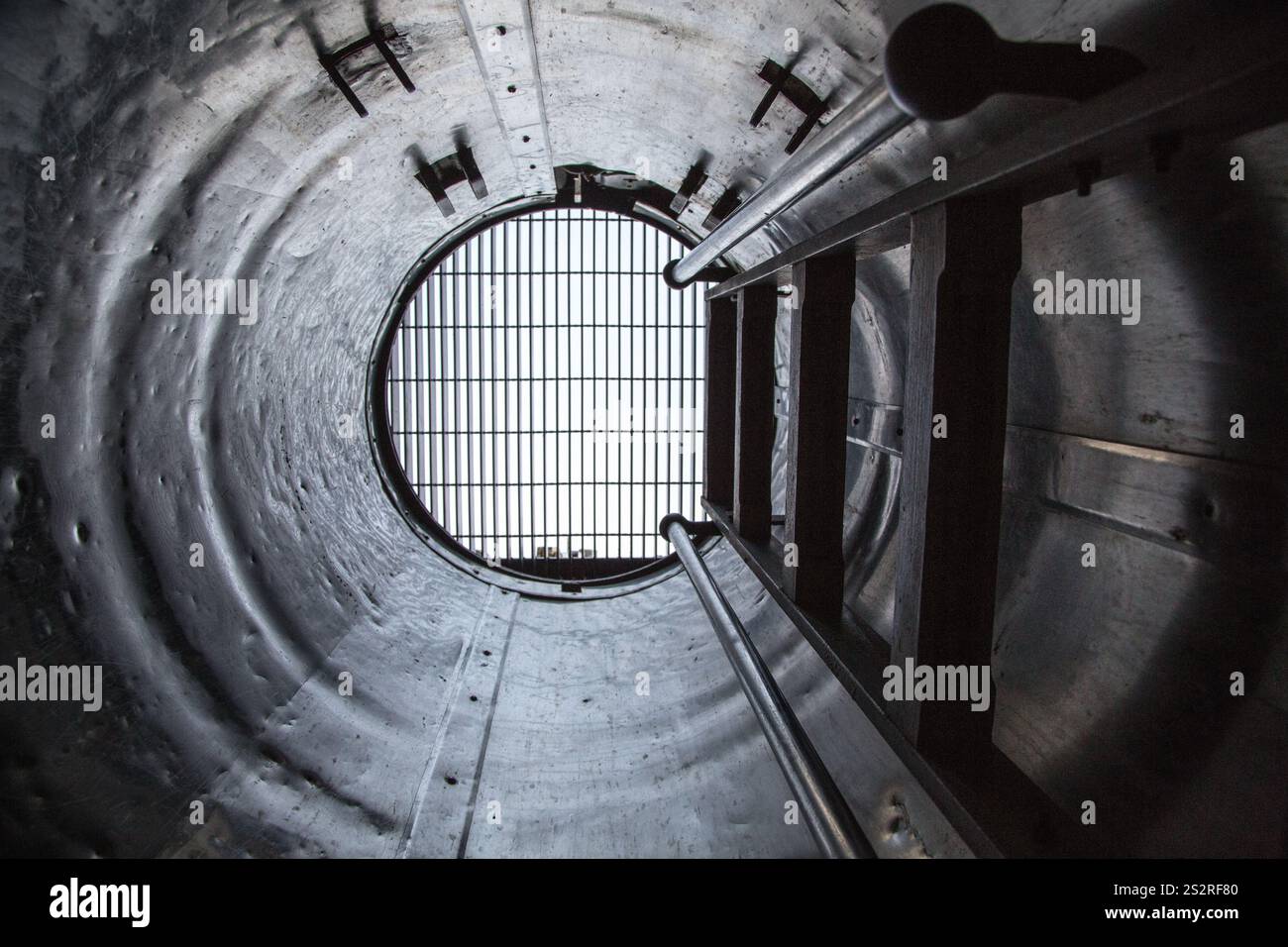A ladder is seen in the middle of a tunnel. The tunnel is dark and the ...