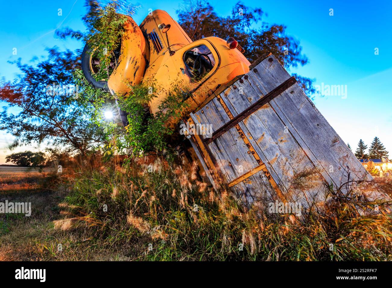 A yellow school bus has crashed into a wooden fence. The bus is upside ...
