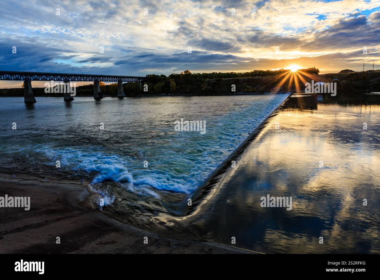 The sun is setting over a body of water, casting a warm glow on the ...
