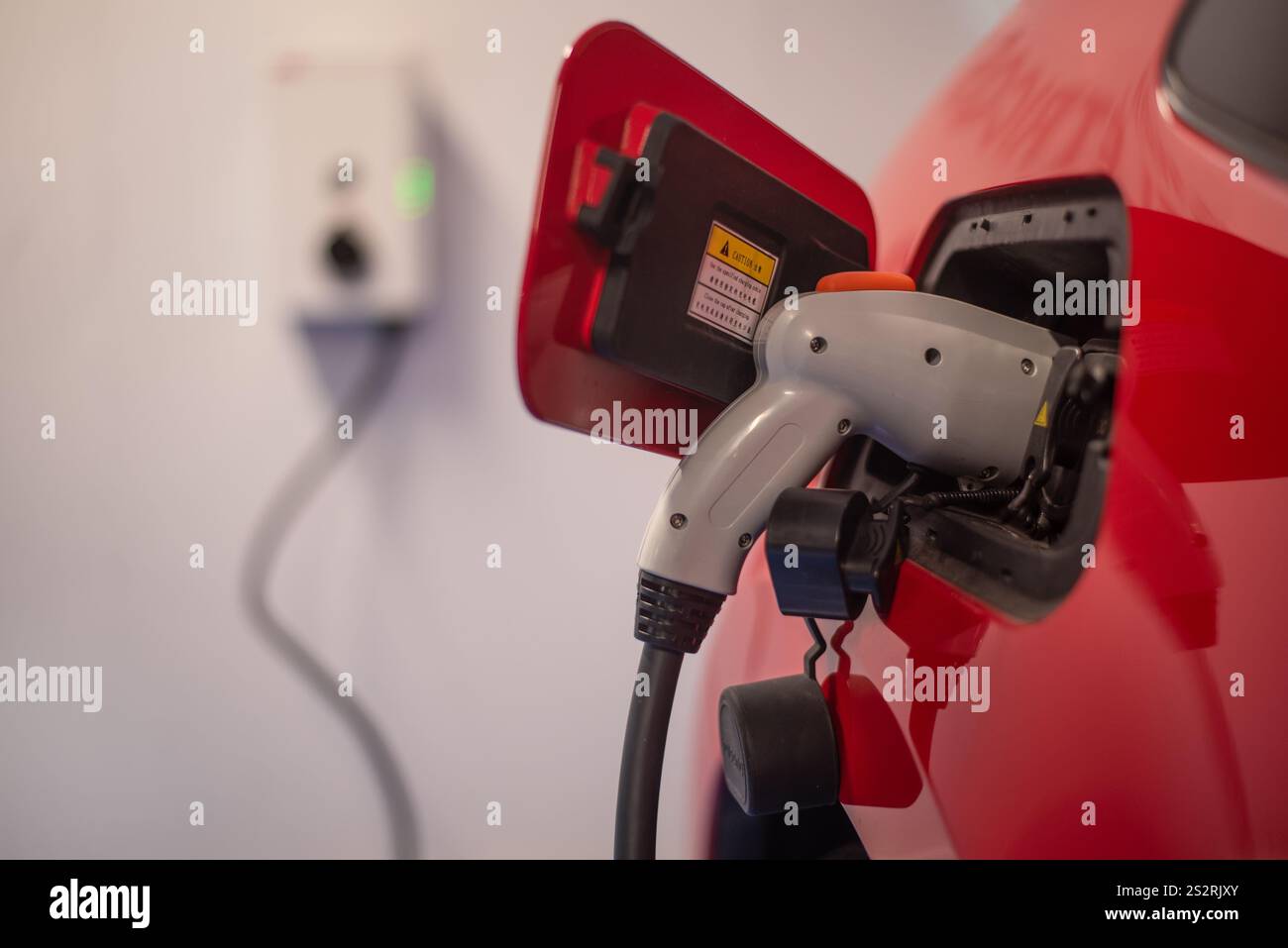 Electric red car being charged Stock Photo - Alamy