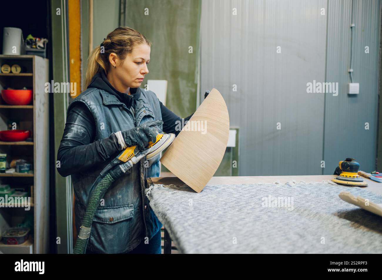 Woman worker engineer carpenter wears safety gloves using wood ...