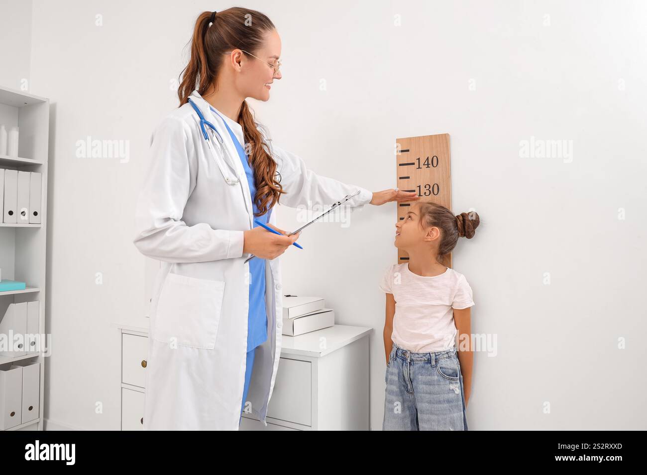 Female pediatrician with little girl measuring height in clinic Stock ...