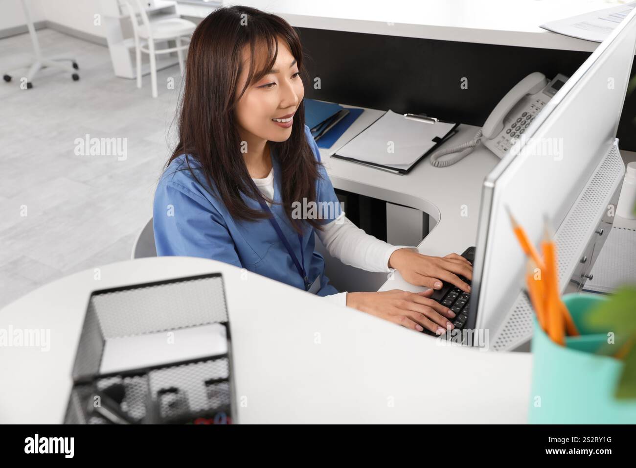 Female Asian medical intern working with computer at reception in ...