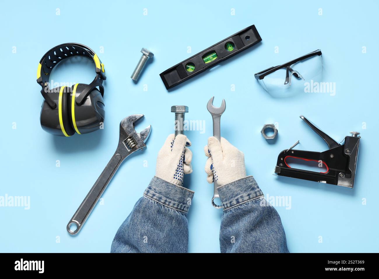 Mechanic's hands with bolt and tools on blue background Stock Photo - Alamy