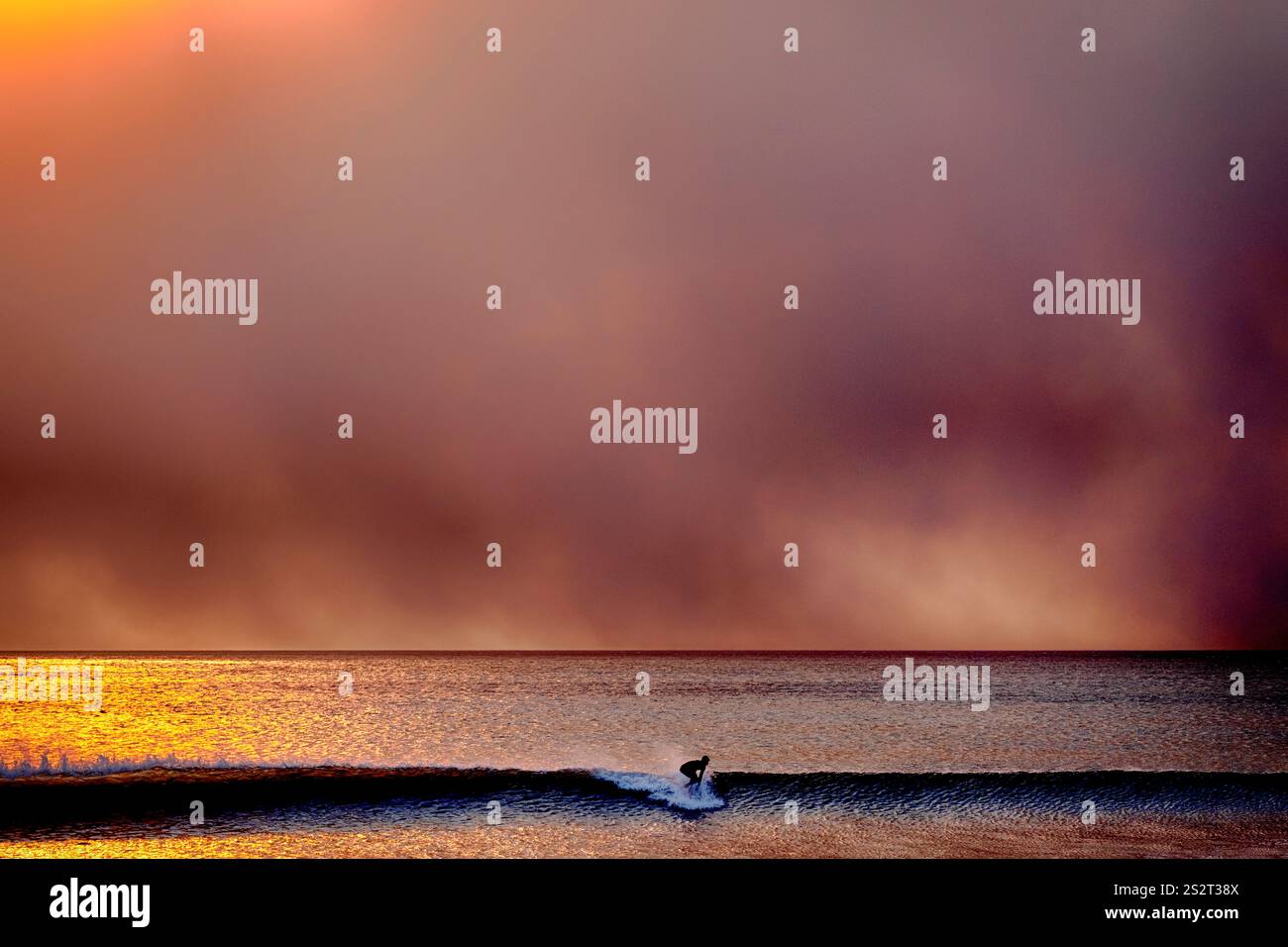 A surfer takes off on a wave in Santa Monica, Calif., during sunset ...