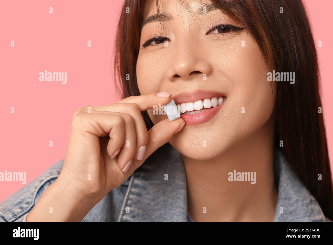 Pretty young Asian woman with chewing gum on pink background, closeup ...