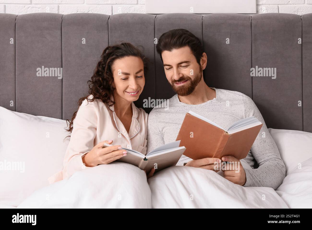 Happy couple reading books under blanket in bedroom Stock Photo - Alamy