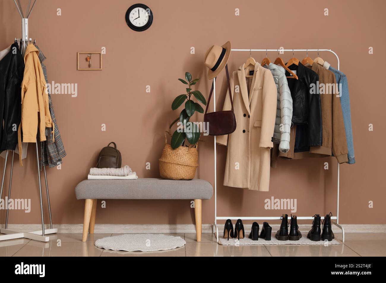 Interior of stylish hall with clothes rack, grey bench, houseplant and ...