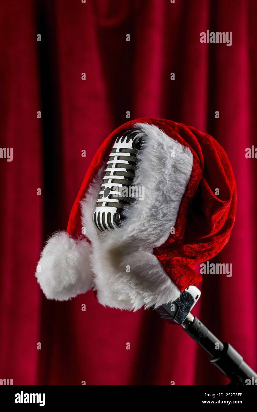 An old retro microphone with a Christmas hat in front of a red velvet ...