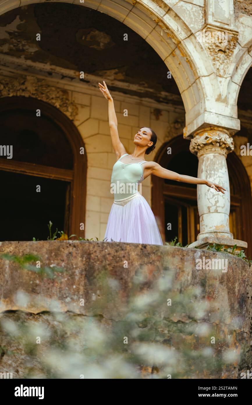 Graceful ballet queen is practicing figures with joy on balcony of old ...