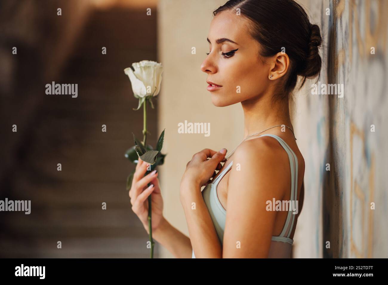 Portrait of a graceful beautiful ballerina in white dress holding a ...