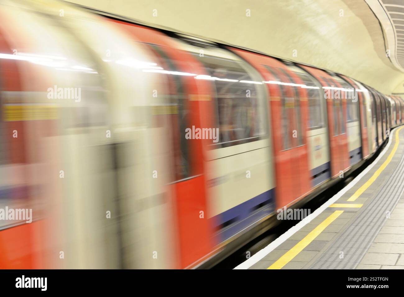 Red underground train in motion on a platform, London, London region ...