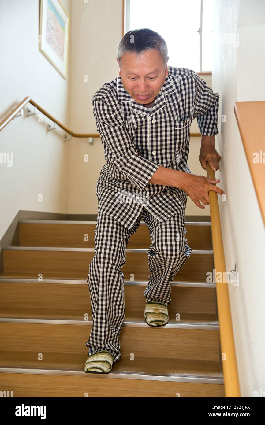 Senior man walking down stairs holding onto handrail Stock Photo - Alamy