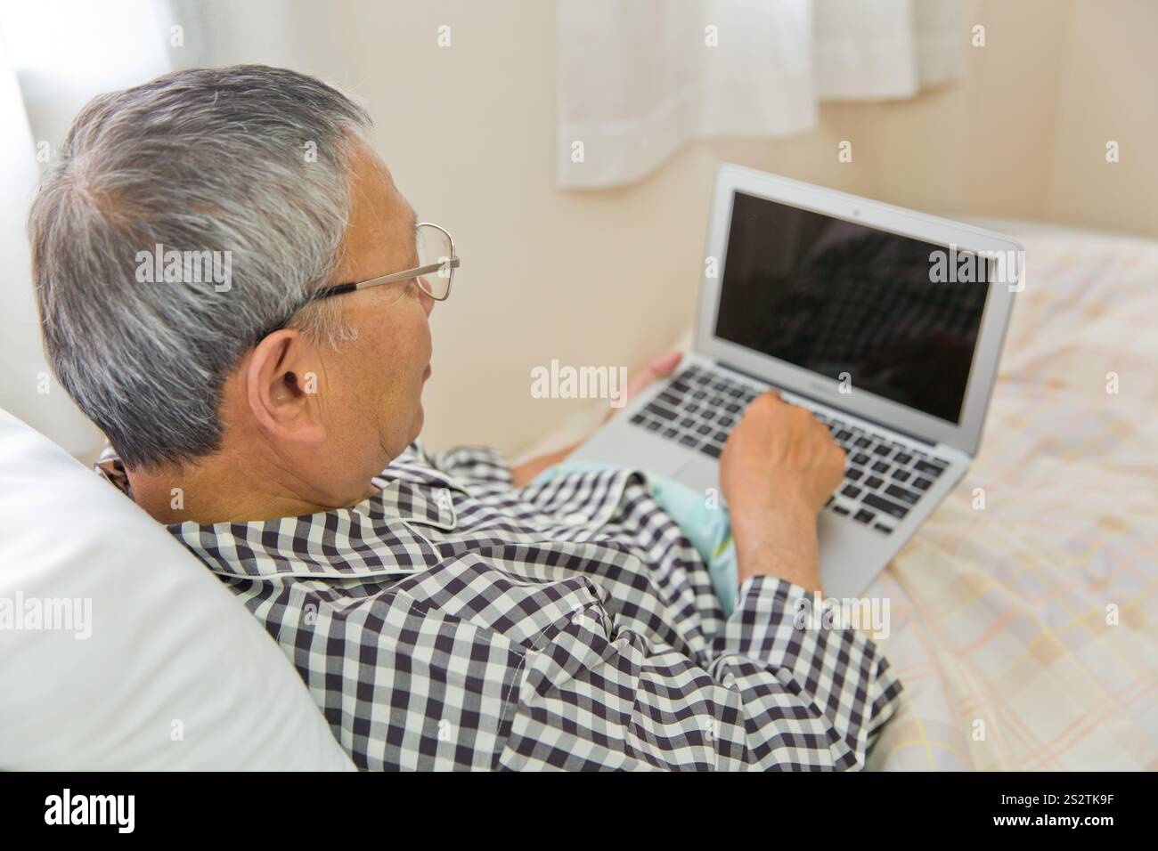 Senior male patient using computer in bed Stock Photo - Alamy