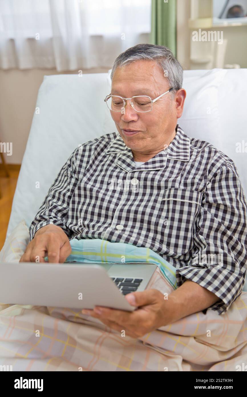 Senior male patient using computer in bed Stock Photo - Alamy