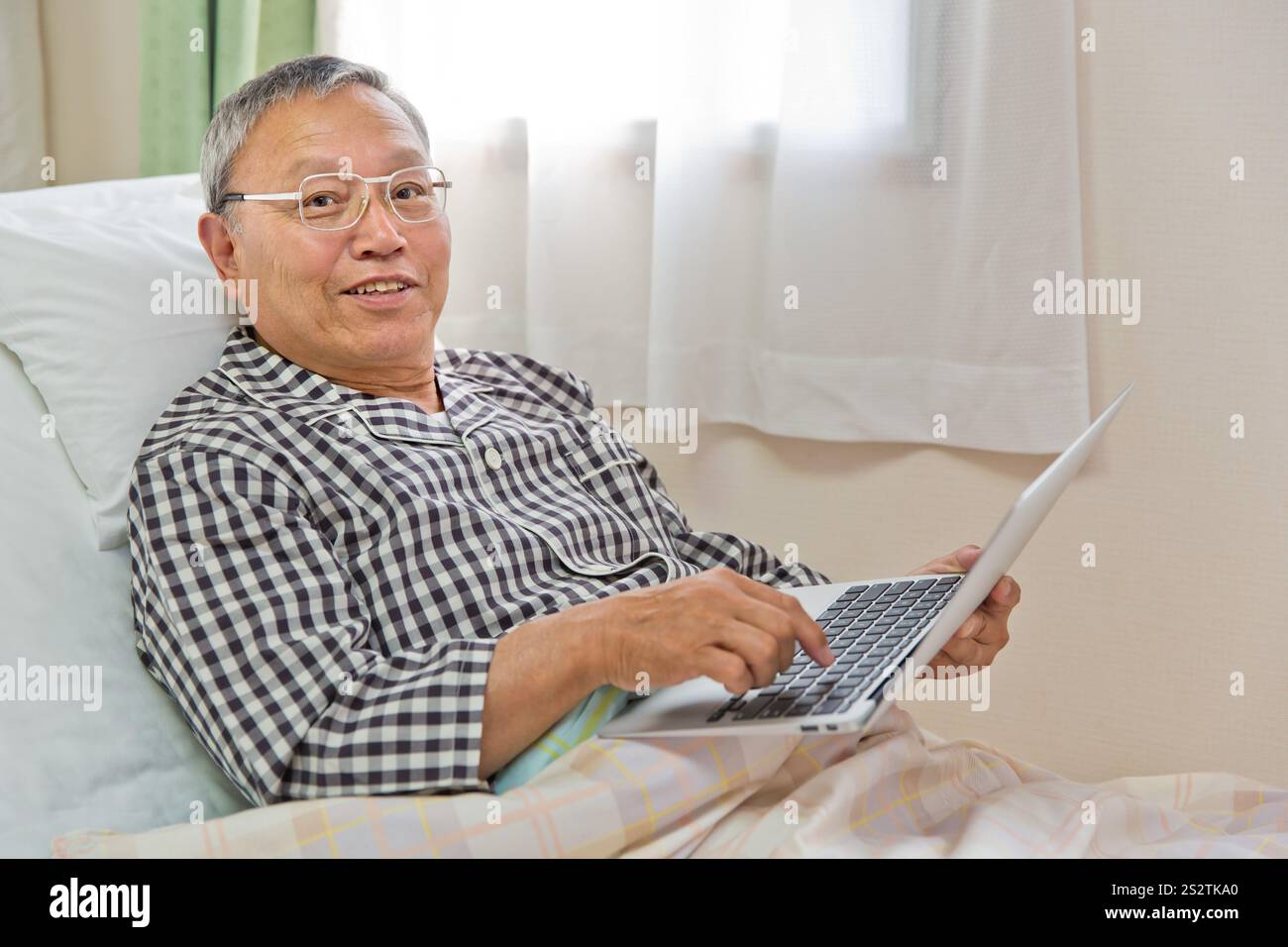 Senior male patient using computer in bed Stock Photo - Alamy