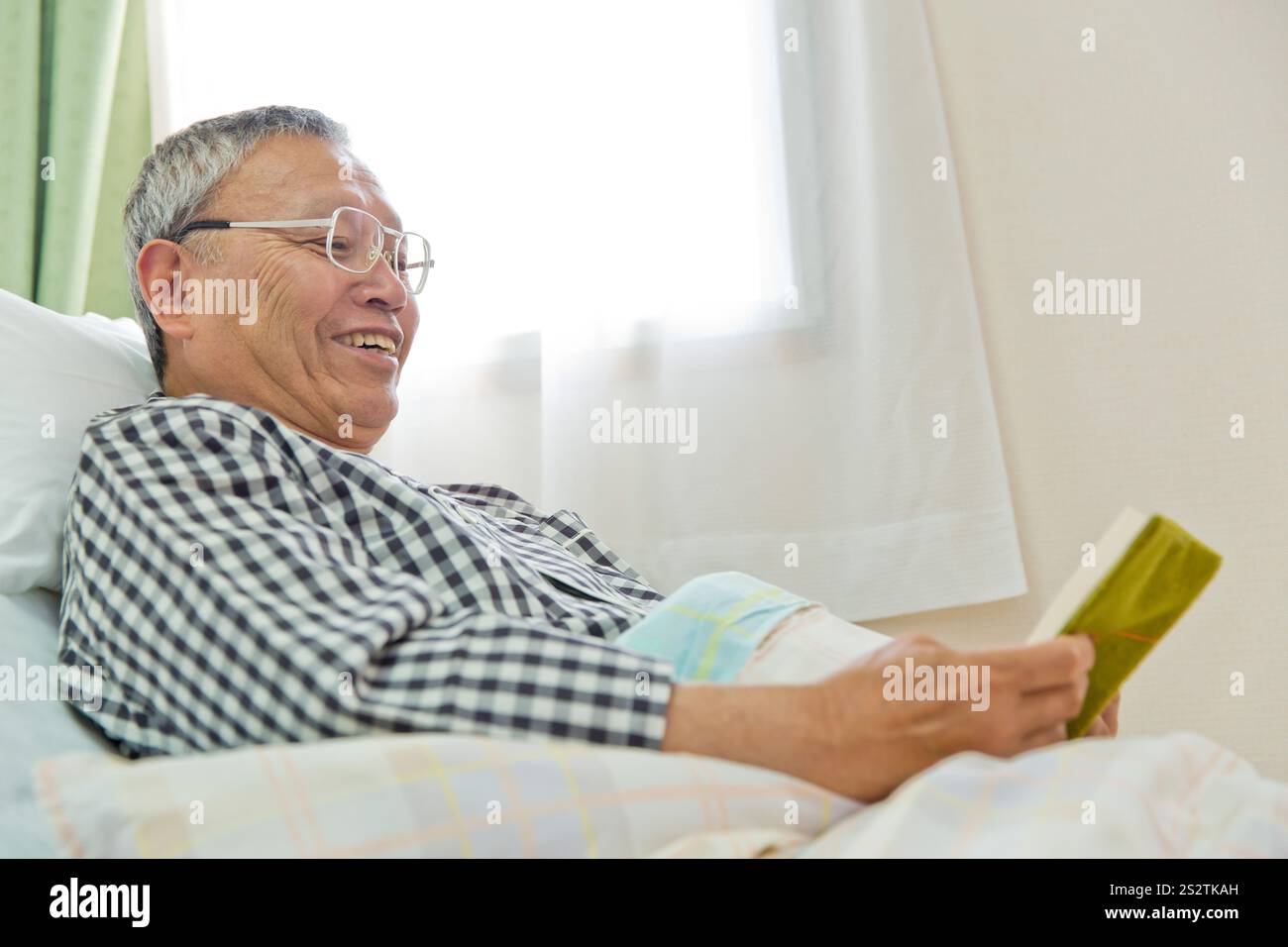 Senior male patient reading book in bed Stock Photo - Alamy