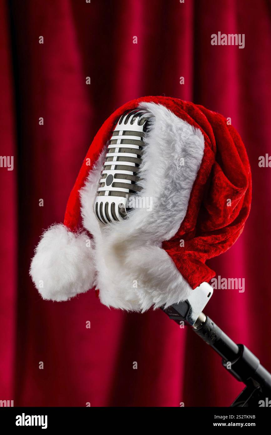 An old retro microphone with a Christmas hat in front of a red velvet ...