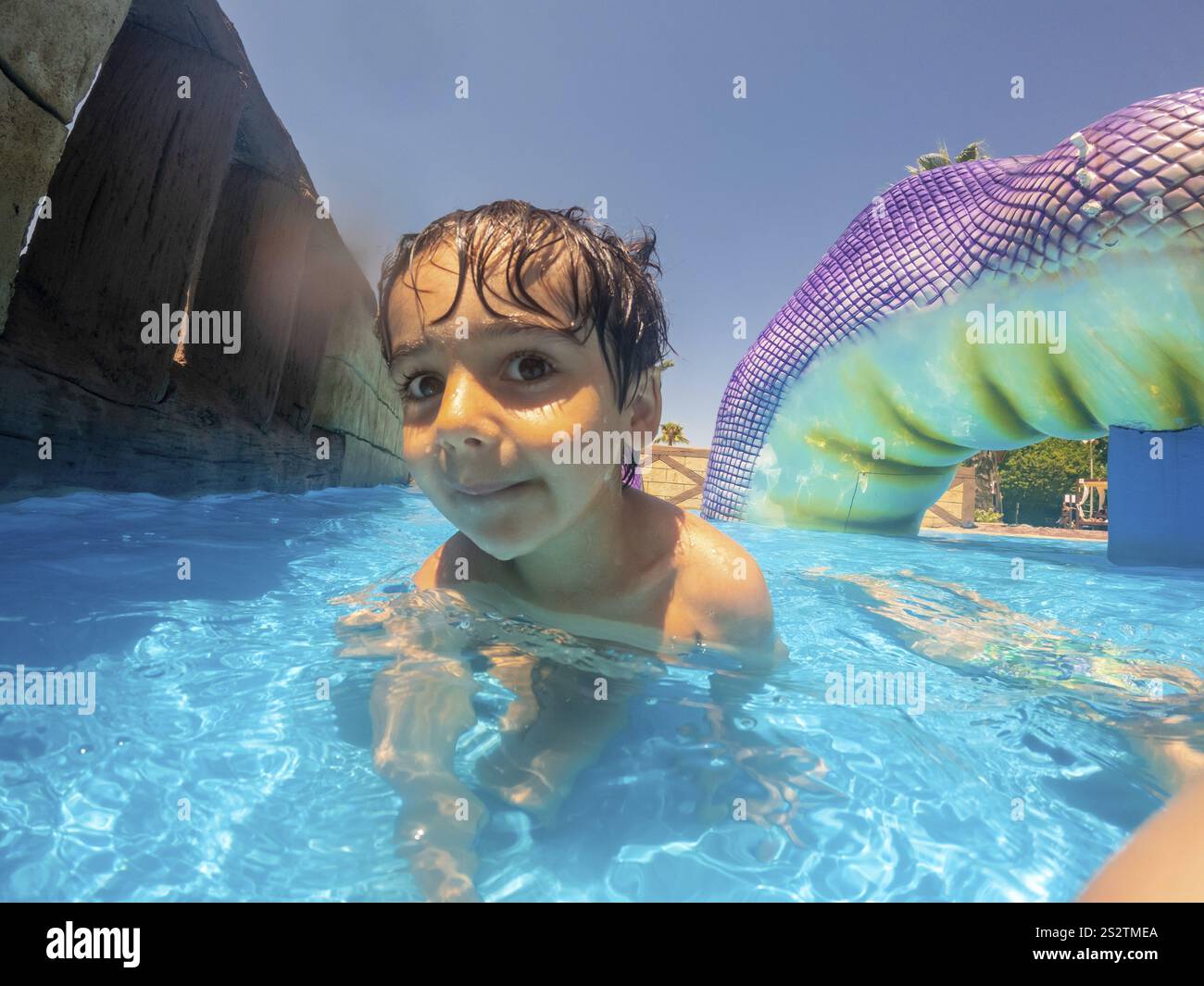 Young boy swimming in blue pool at water park, enjoying summer vacation ...