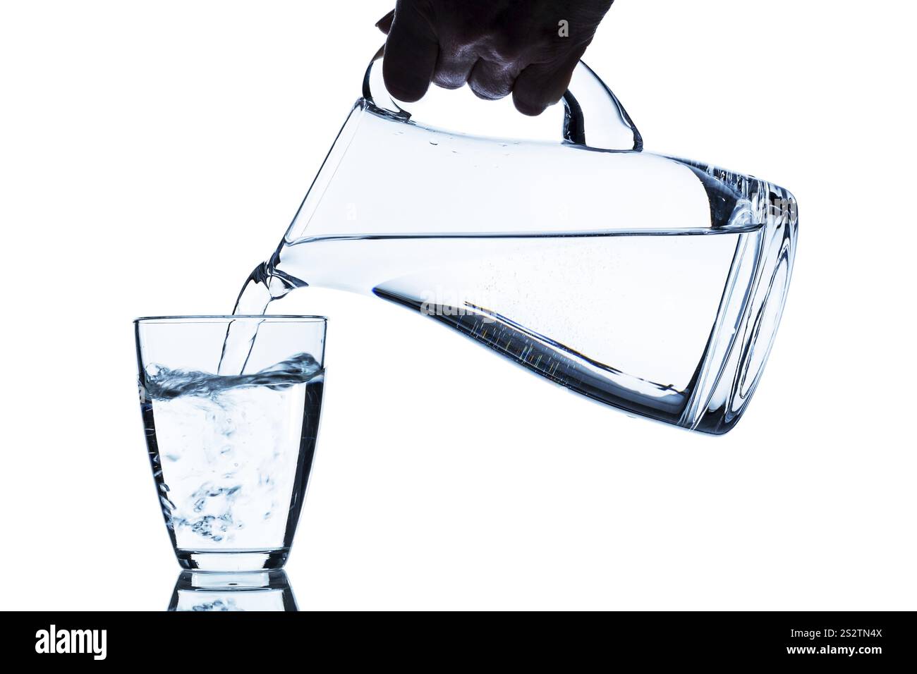 Pure water is poured into a water glass from a jug. Fresh drinking ...