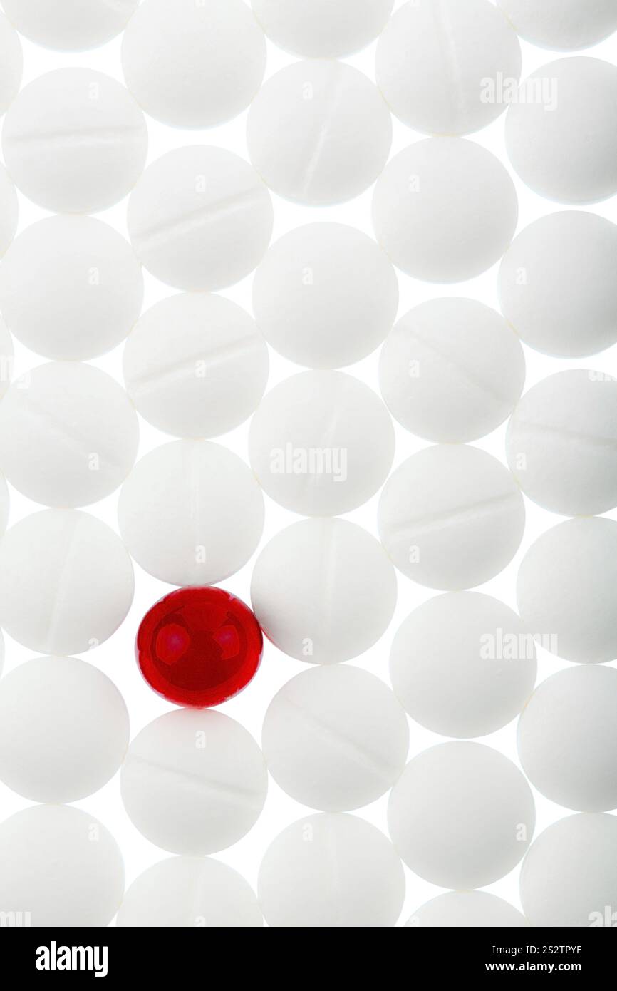 White tablets in contrast with a red tablet, symbolic photo for ...