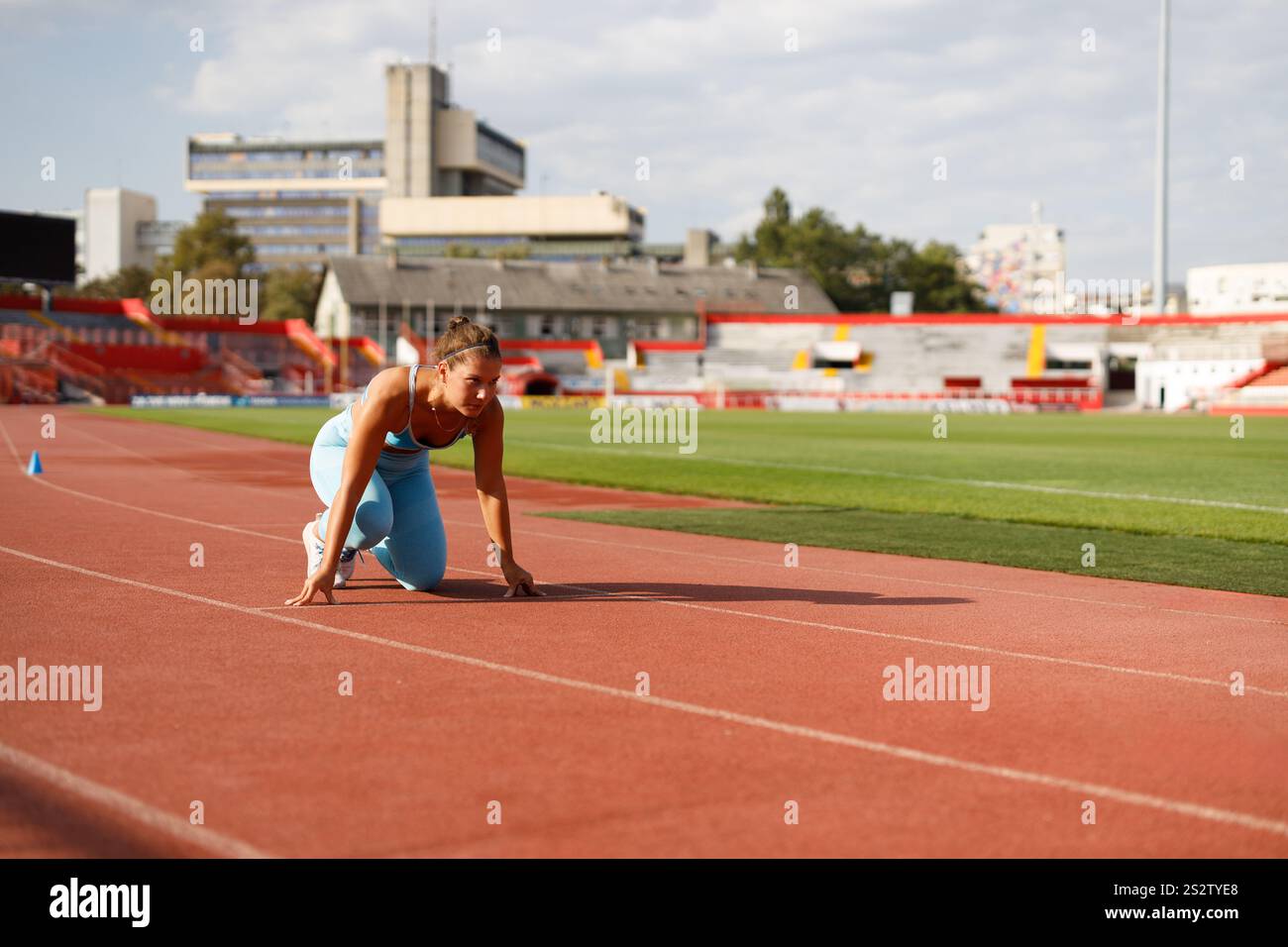 Determinate female sprinter athlete getting ready to start a race on a ...