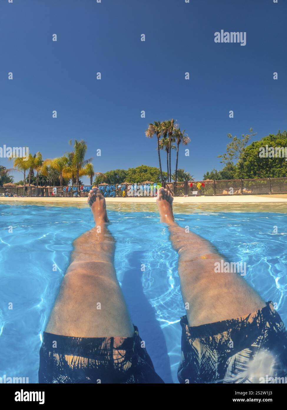 Legs of a tourist floating and relaxing in a swimming pool at a water ...