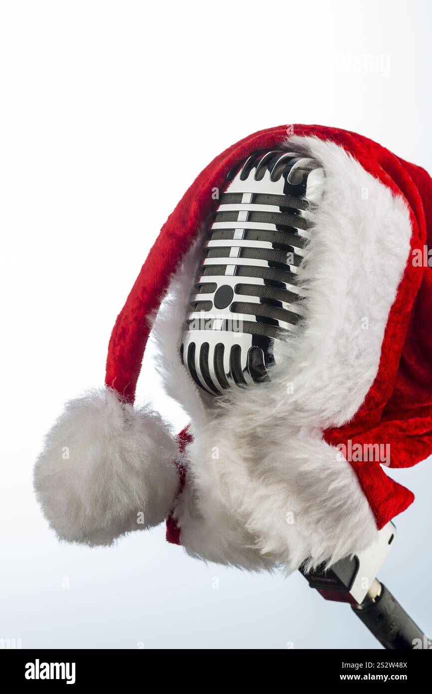 An old retro microphone with a Christmas hat in front of a red velvet ...