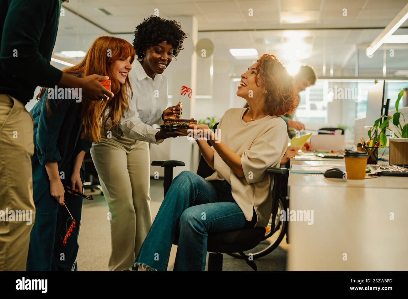A surprised businesswoman is having a birthday surprise at the office ...