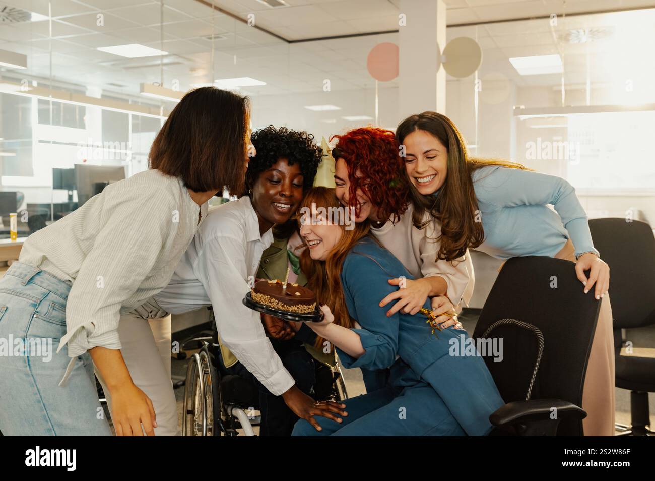 Businesspeople are hugging a bday girl at the office while having ...
