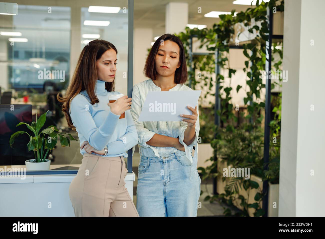 Couple of sad and disappointed diverse businesswoman looking into paper ...