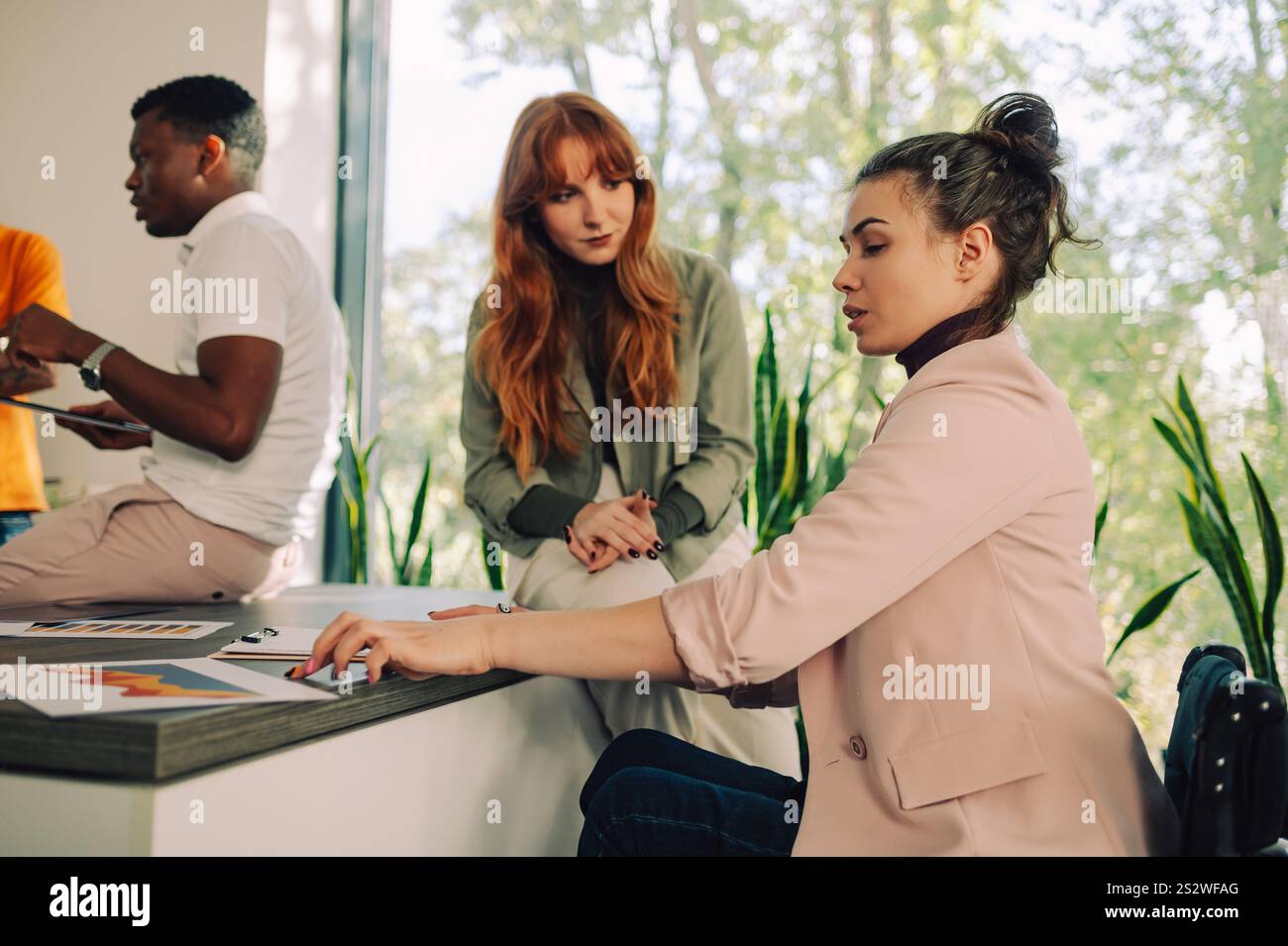 A businesswoman who uses a wheelchair is showing charts and graphs at ...