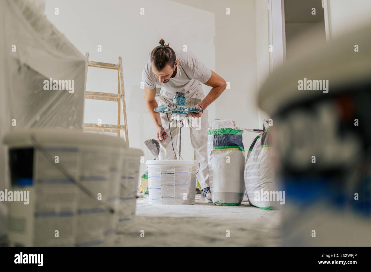 A laborer is standing in a messy house in a renovation process and ...