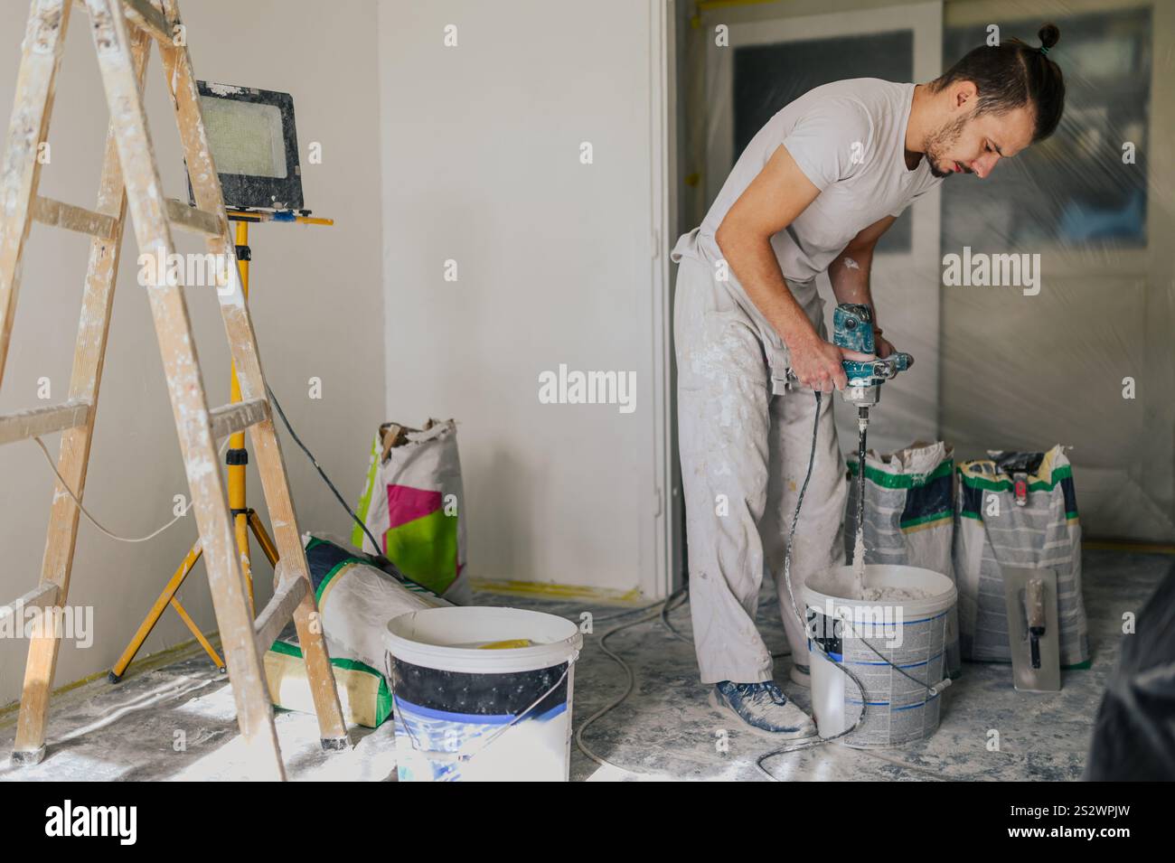 A house painter is standing in a house in a renovation process and ...