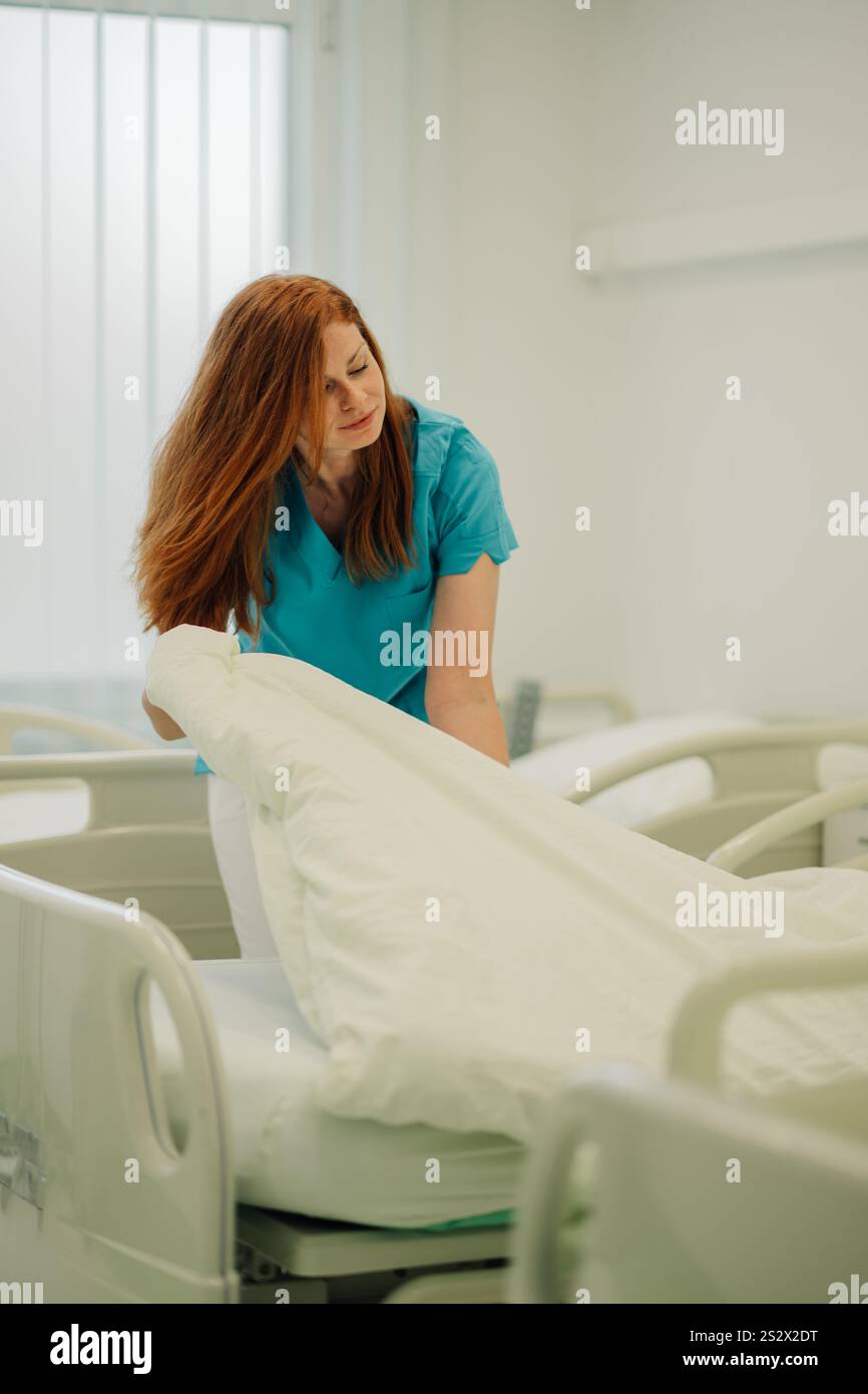 A red-haired nurse ensuring a hospital bed is ready for incoming ...