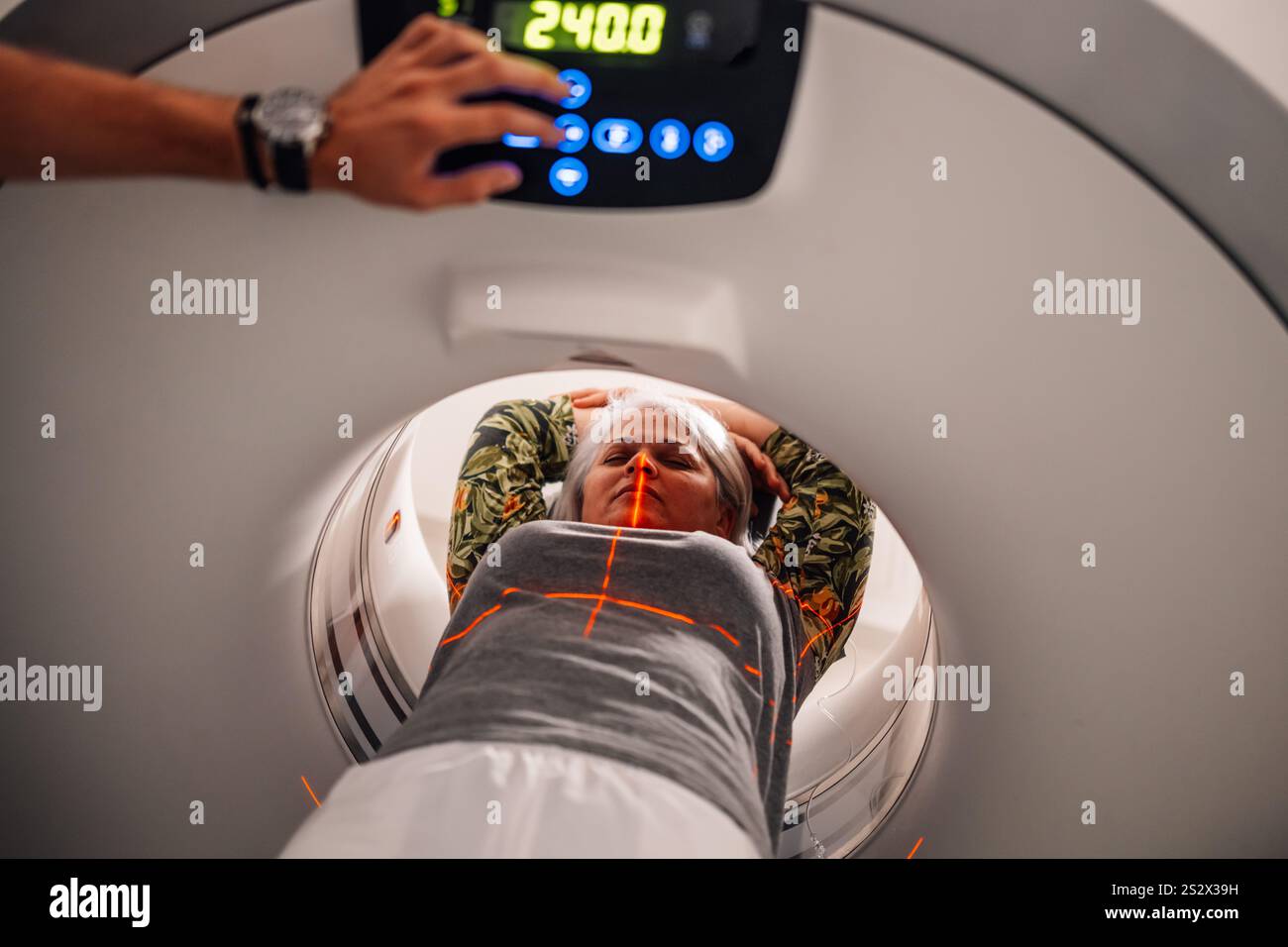 A healthcare professional is actively operating a CT scan machine ...